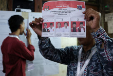Tallying the vote: A local poll administrator (KPPS) shows a ballot on Nov. 27 during the vote counting process for the Jakarta gubernatorial election at a polling station in Jakarta.