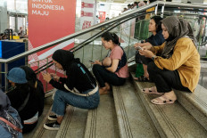 Women use smartphones on Sept. 28, 2023, at the entrance of Tanah Abang Market, Southeast Asia's largest wholesale shopping center for garments and textiles, in Jakarta.