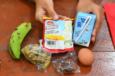 A student of state junior high school (SMPN) 1 Denpasar in Bali shows a variety of food items received as part of the government free meals program on March 17, 2025. 